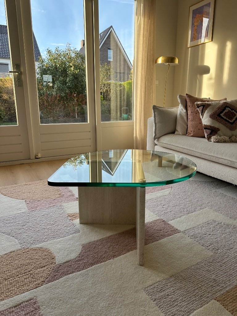 Glazen druppelvormige salontafel op travertin poot | €425 | Whoppah